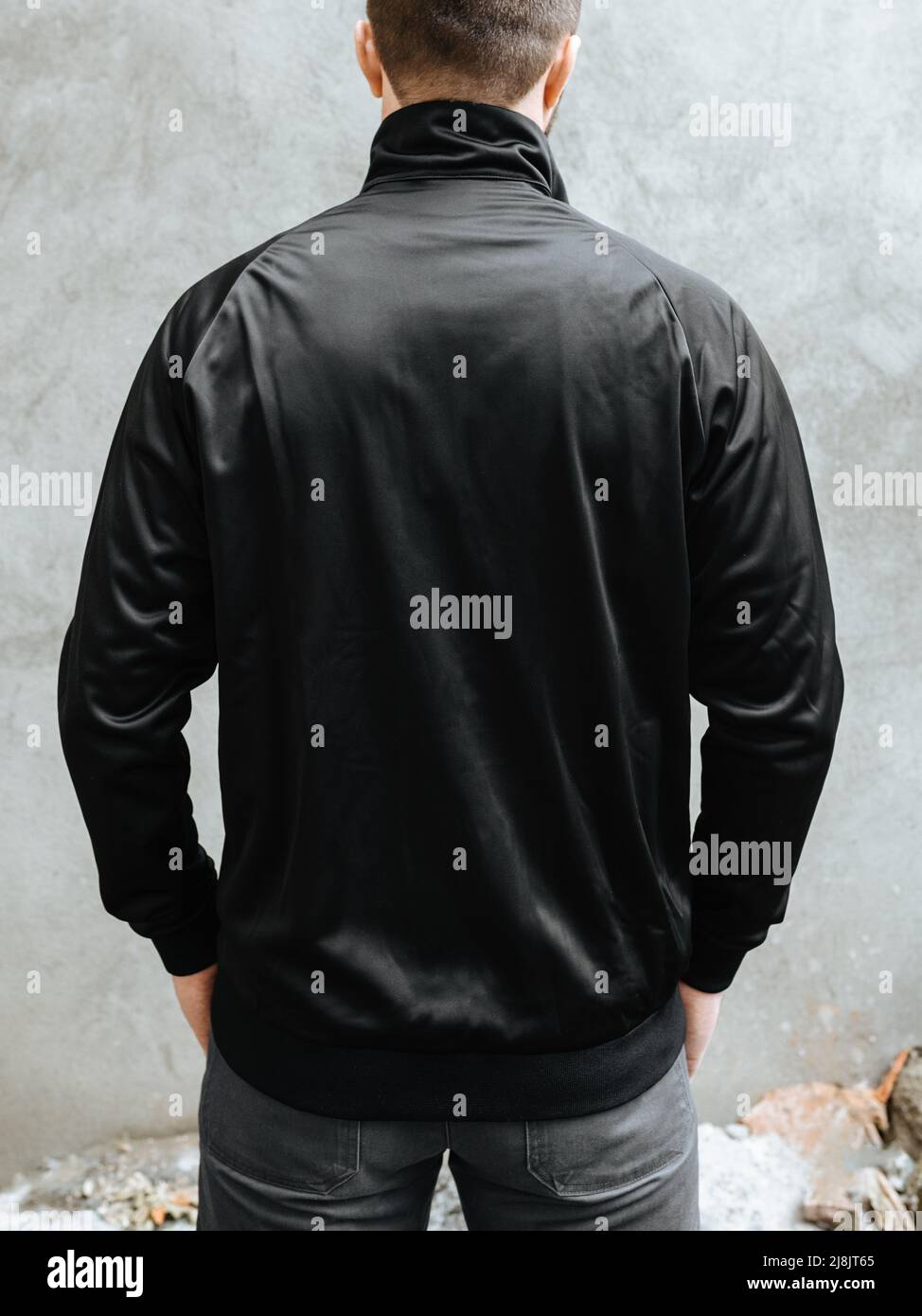 Young man in a black sports jacket. Rear view on a background of light ...