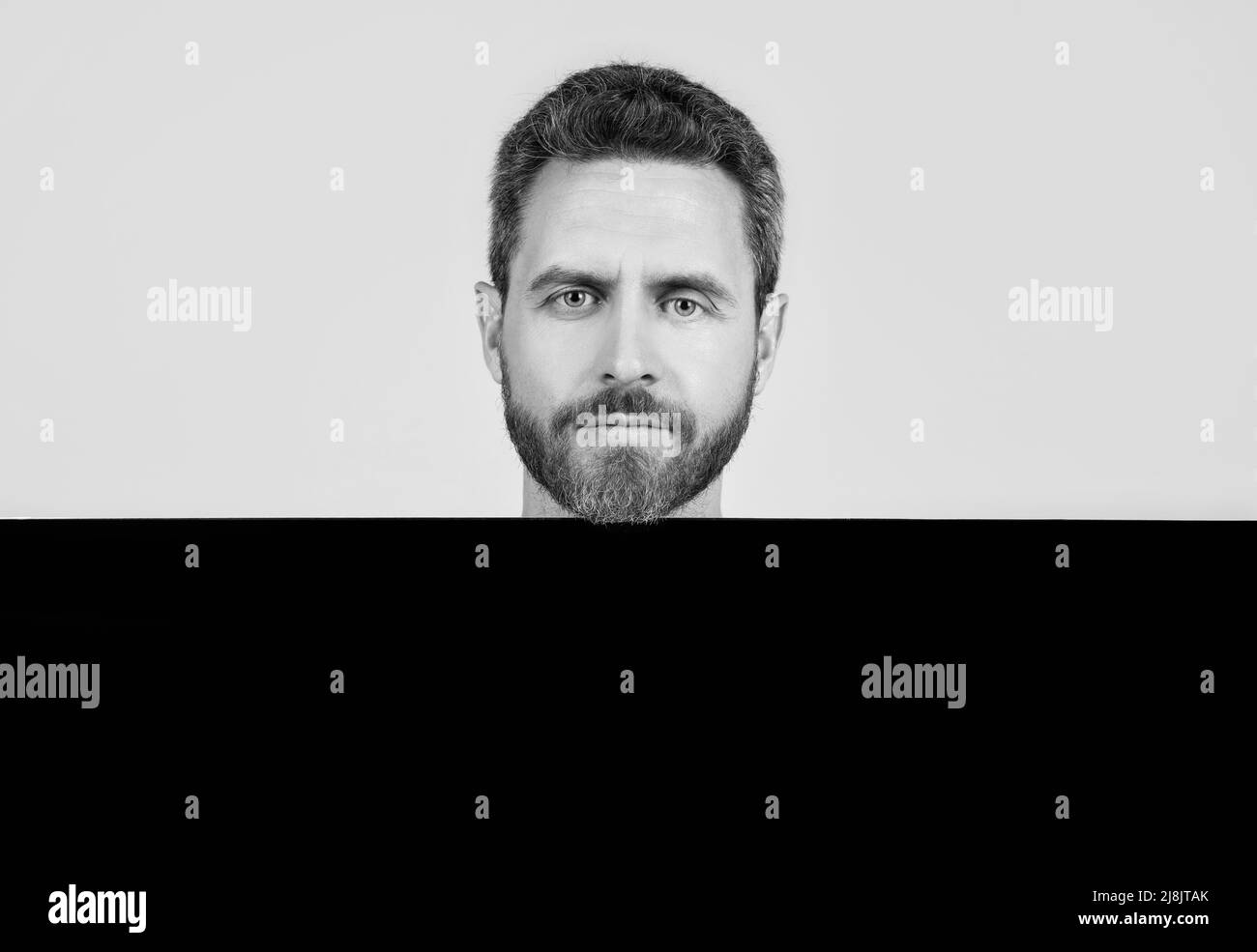 mature bearded man behind blank black paper banner with copy space for ...