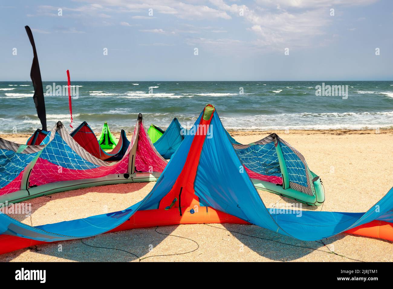 Close-up many bright kitesurf wings and kite equipment sand beach shore ...