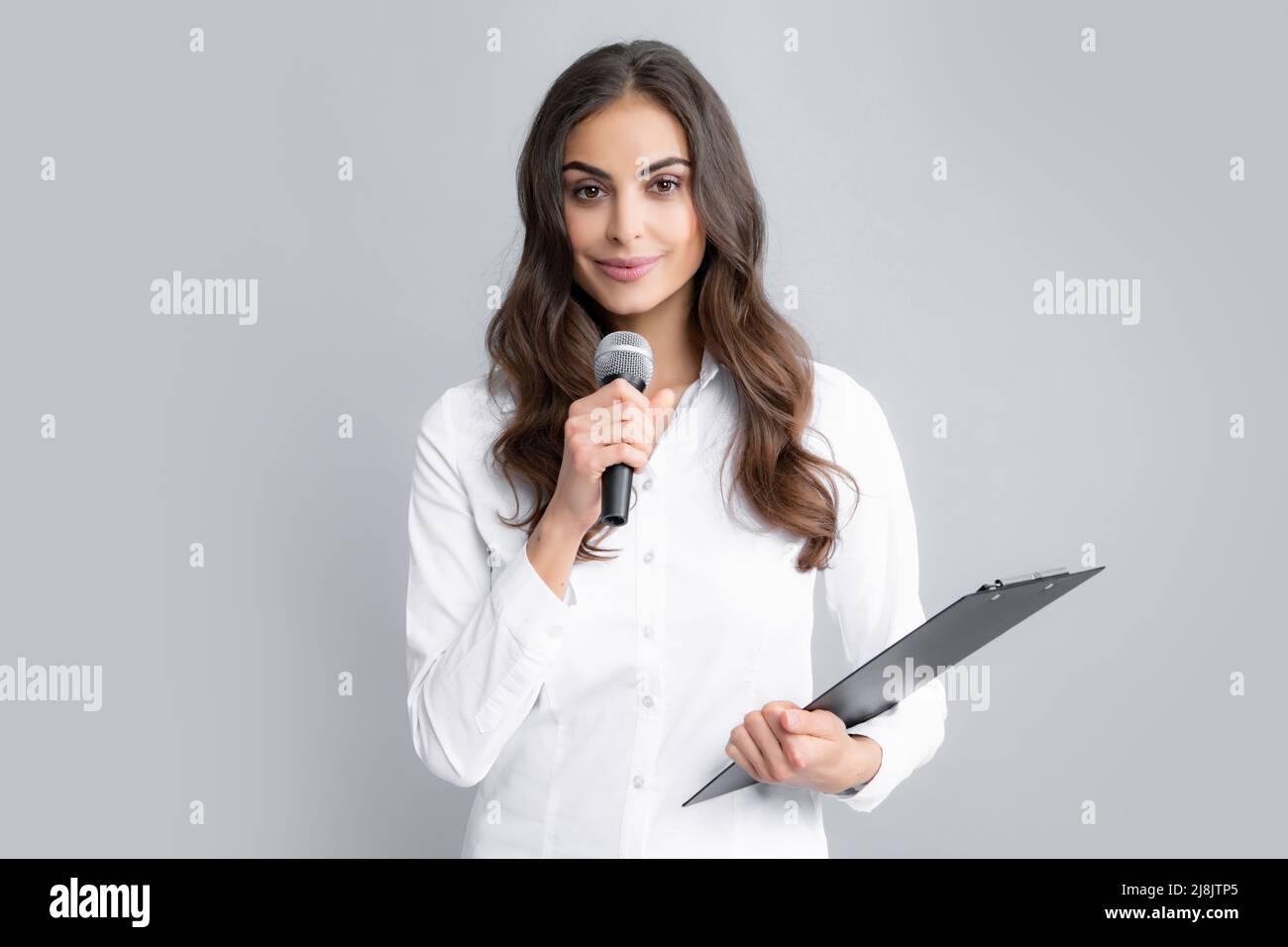 Smiling young woman as reporter with microphone and clipboard. Female ...