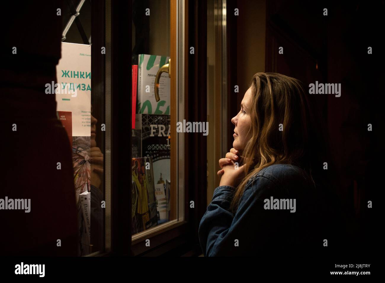 Girl looking though the window of the book shop Stock Photo - Alamy
