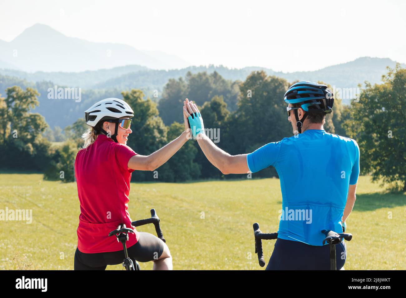 Two road cyclists silhouettes celebrating a ride finish with a high ...
