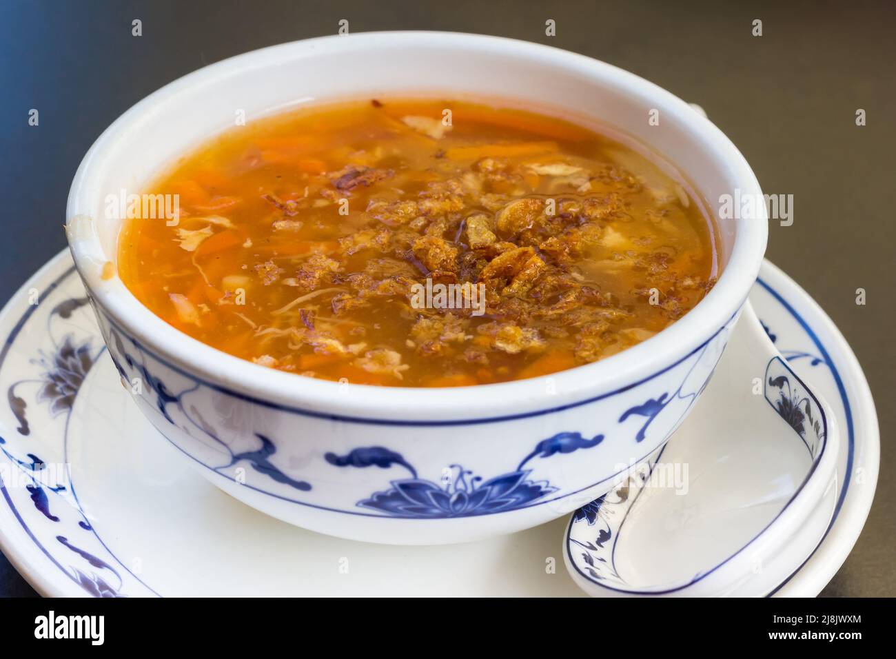 Bowl of traditional chinese sour and spicy soup on a plate with spoon ...