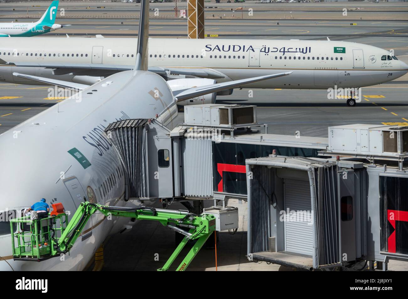 A worker (L) cleans the front window of a flag carrier Saudi Arabia ...