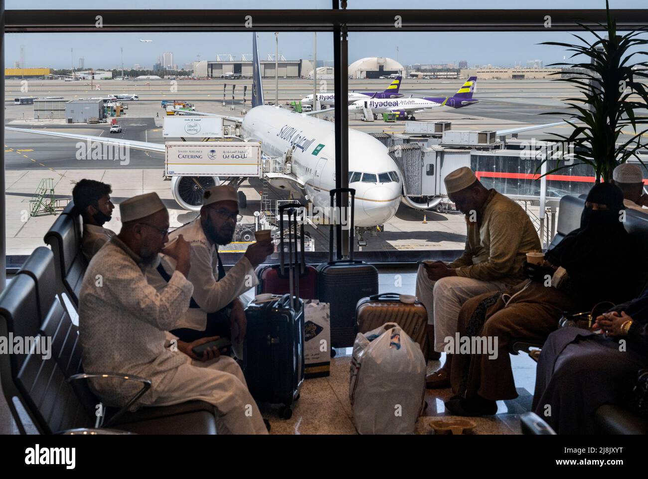 Flight passengers are seated in the waiting area as the flag carrier of ...