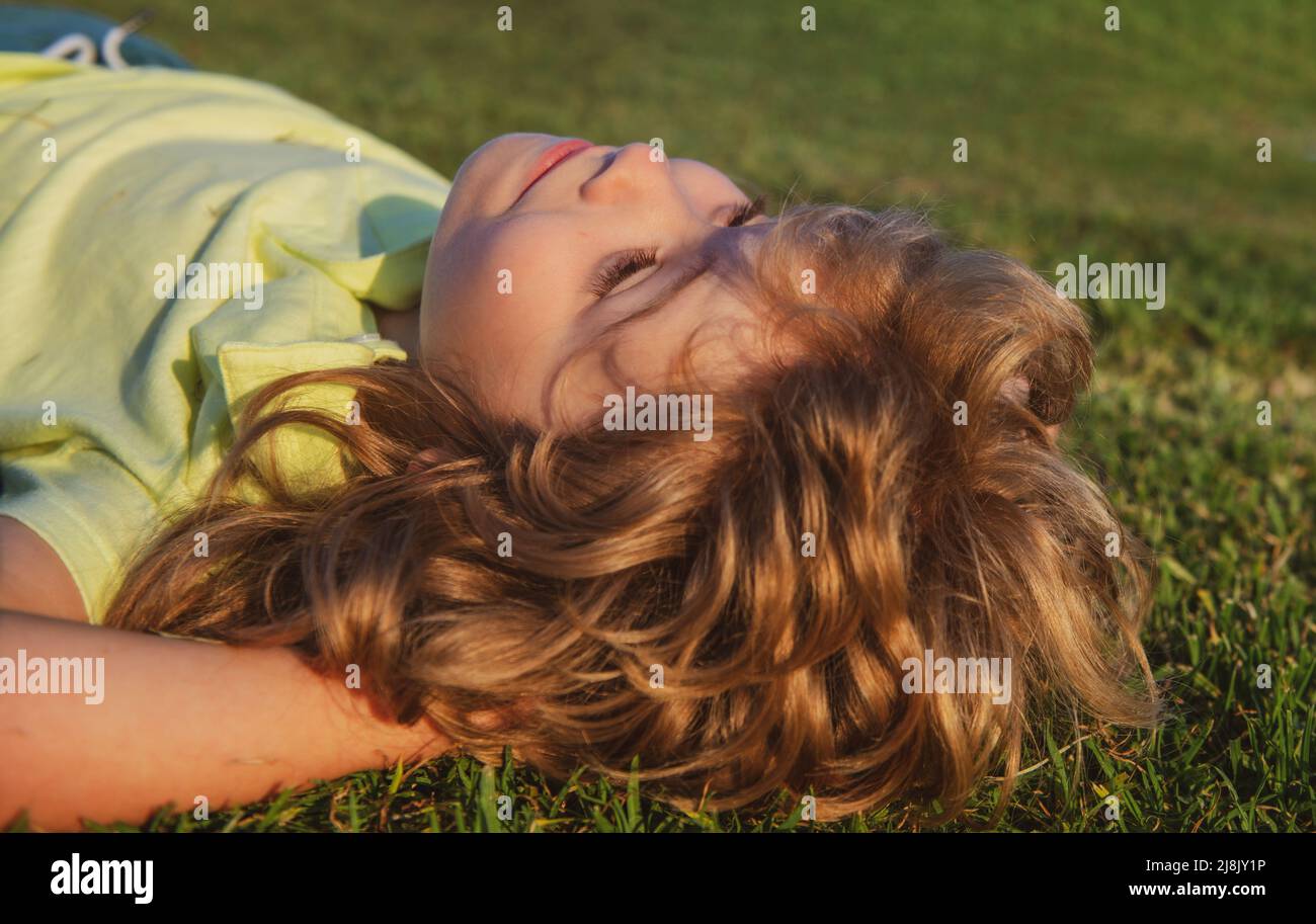 Portraits of happy kids playing and laying on grass outdoors in summer ...