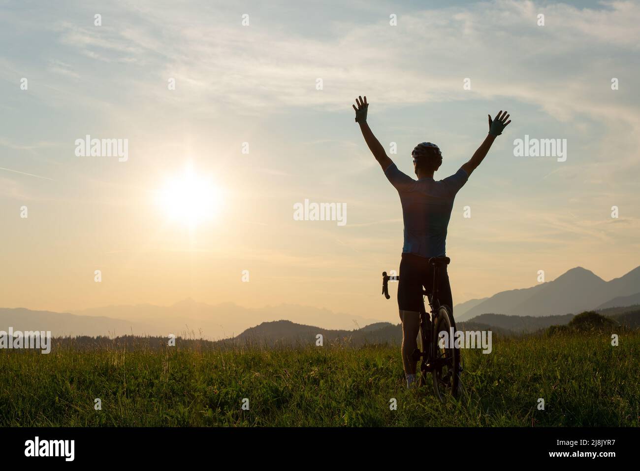 Male racing cycle rider celebrating the win with arms raised above his ...