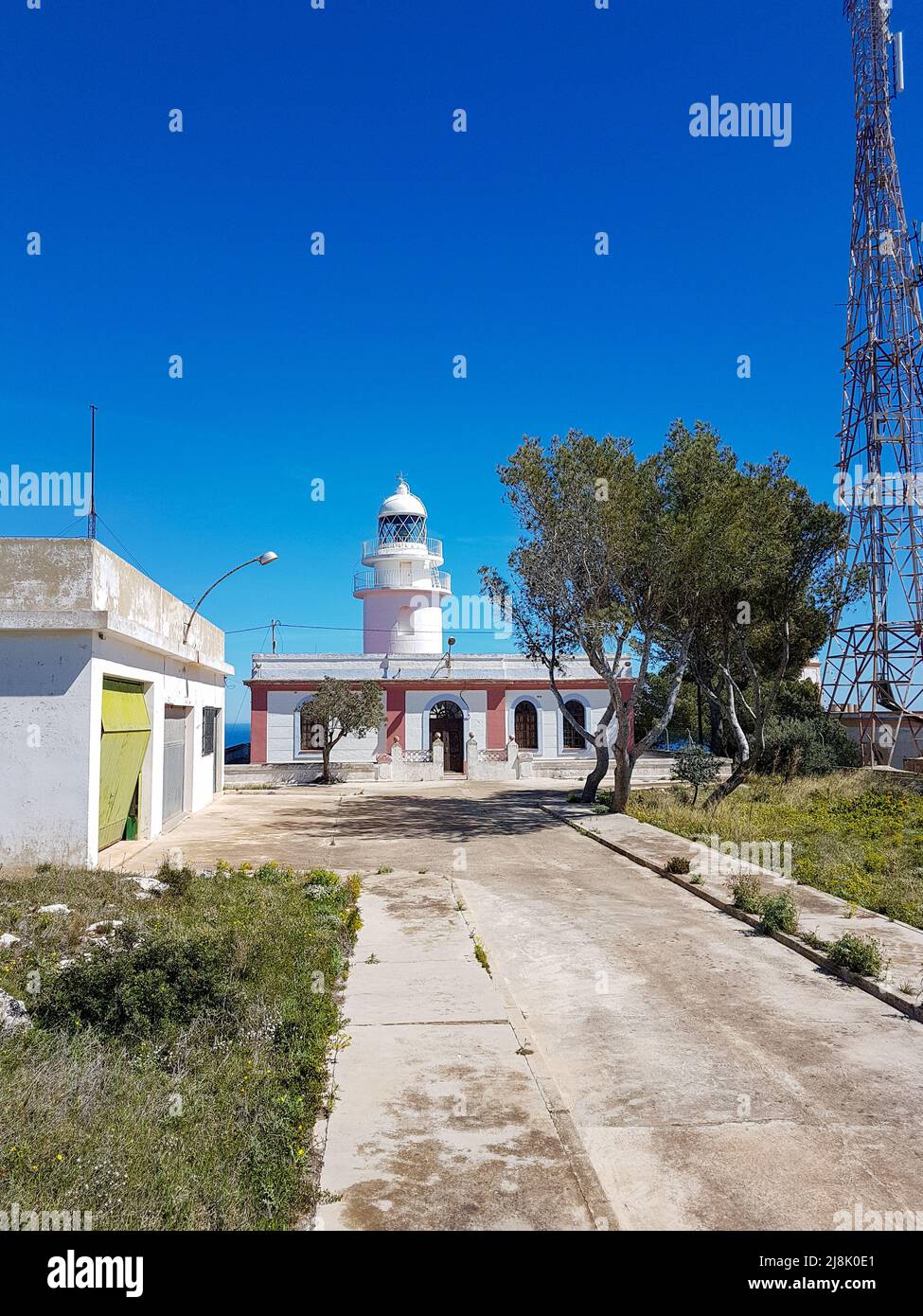 A small old white lighthouse and a large radio mast, on the Spanish ...