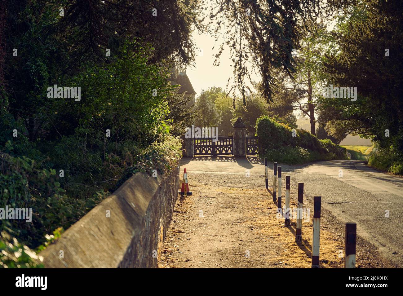 looking down country lane into yellow sun with view of church and Stock ...