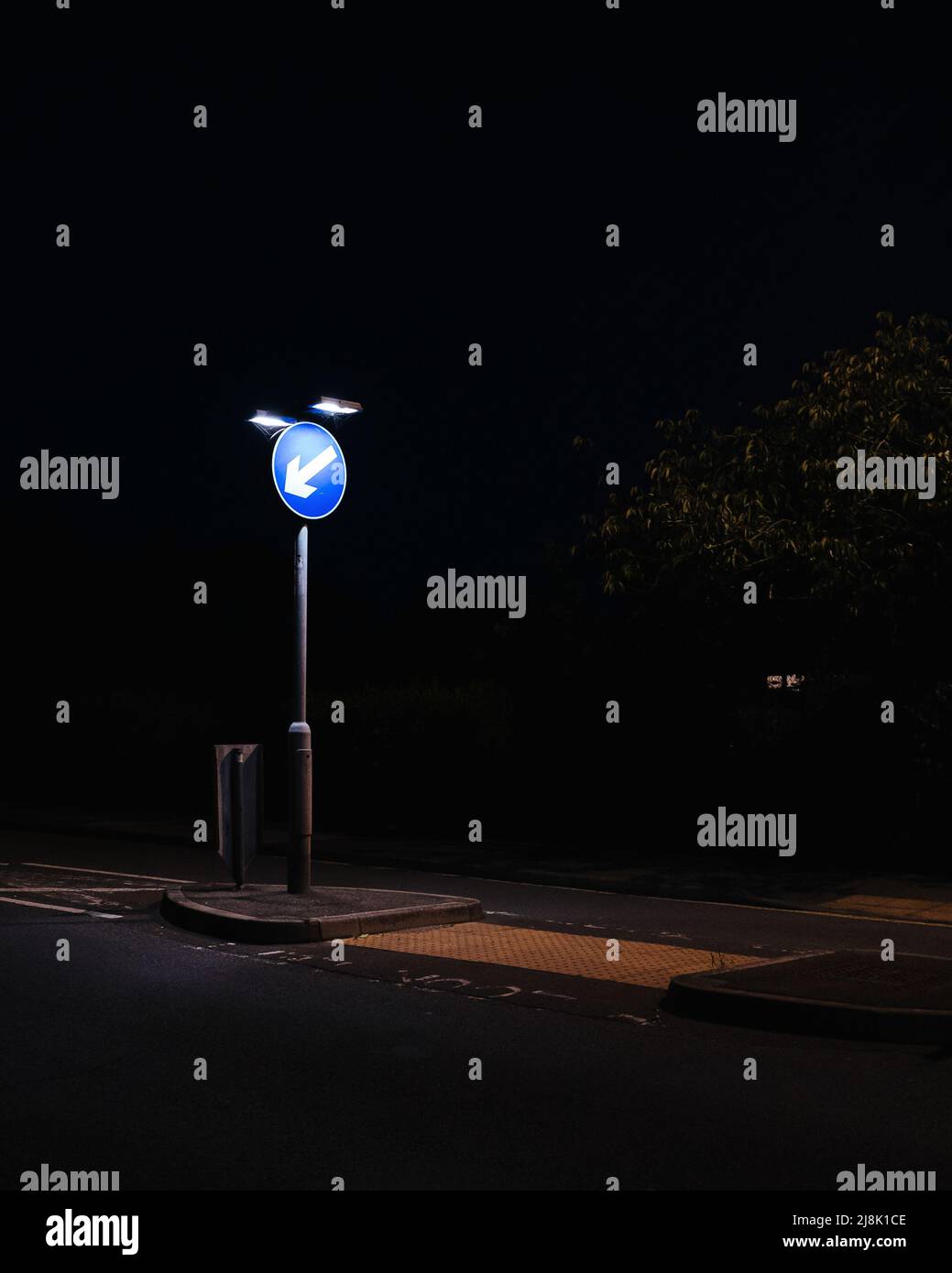 Vertical shot of 'Keep Left' British road sign at night with contrasted ...
