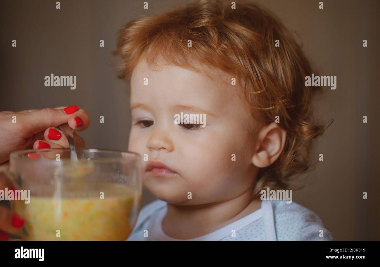 Mother giving healthy food to her adorable child at home. Feeding kids ...