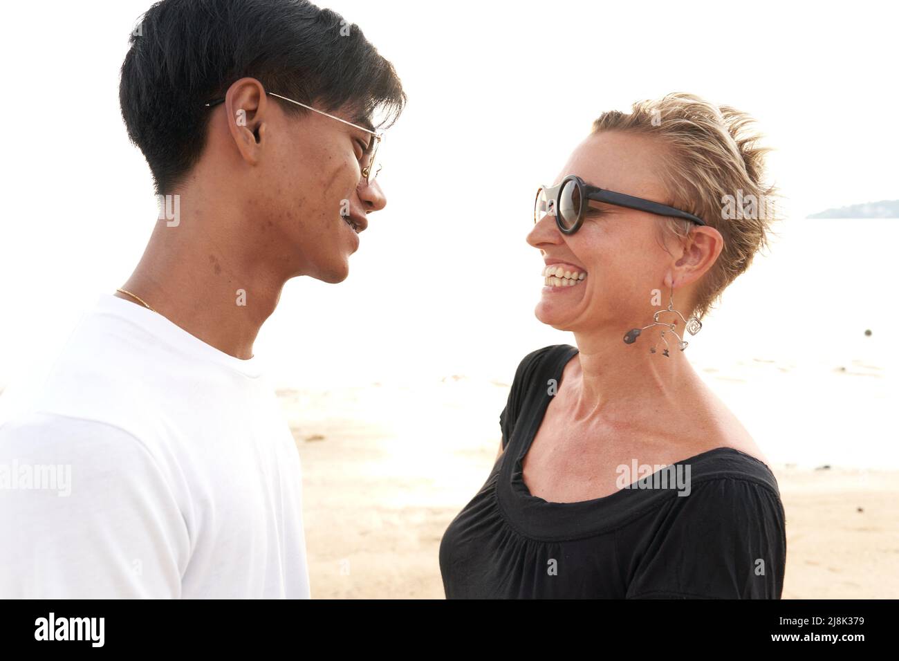 Multicultural couple smiling to each other in a sandybeach Stock Photo ...