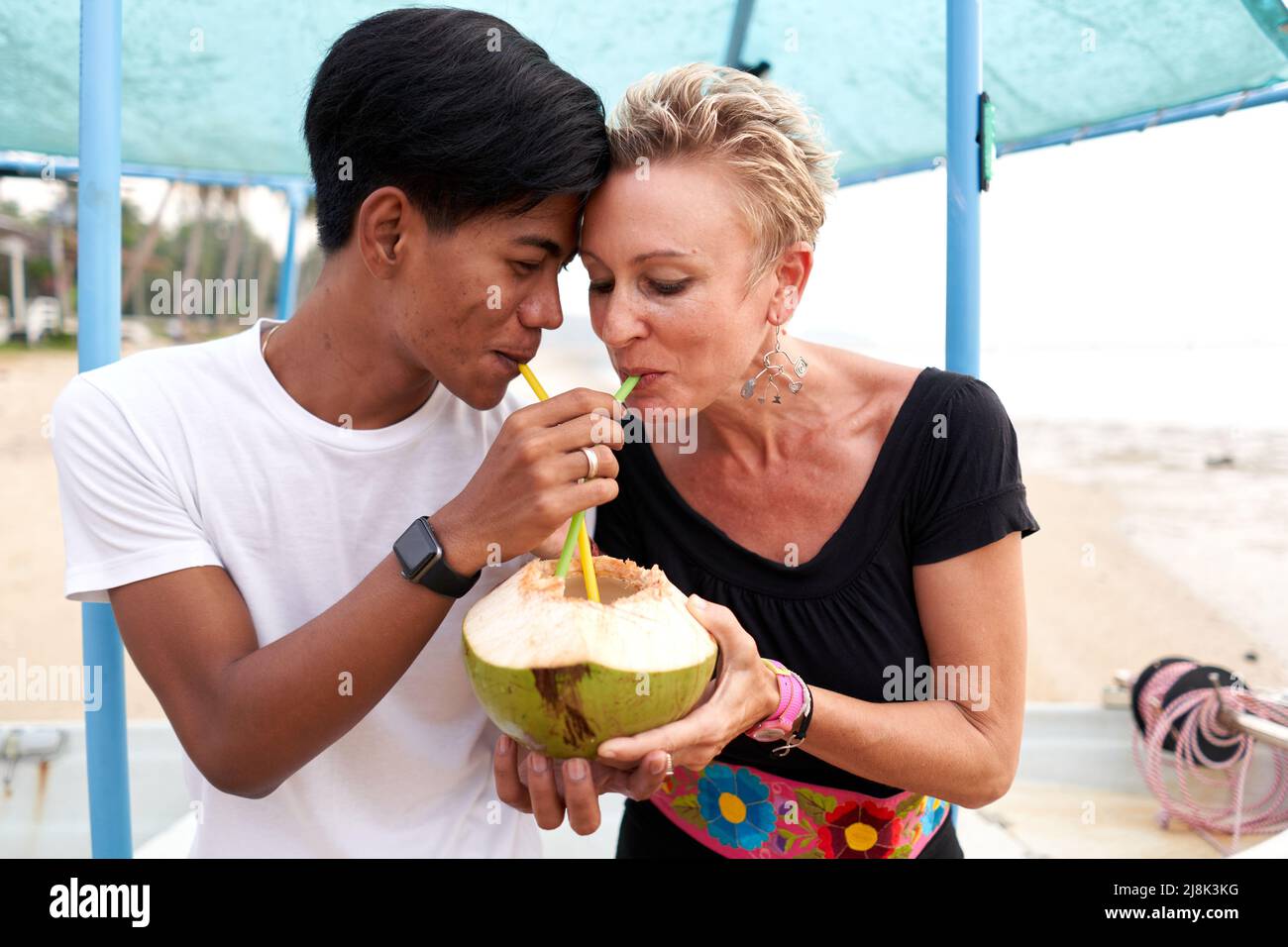 Multicultural couple sharing the juice of a fresh coconut Stock Photo ...