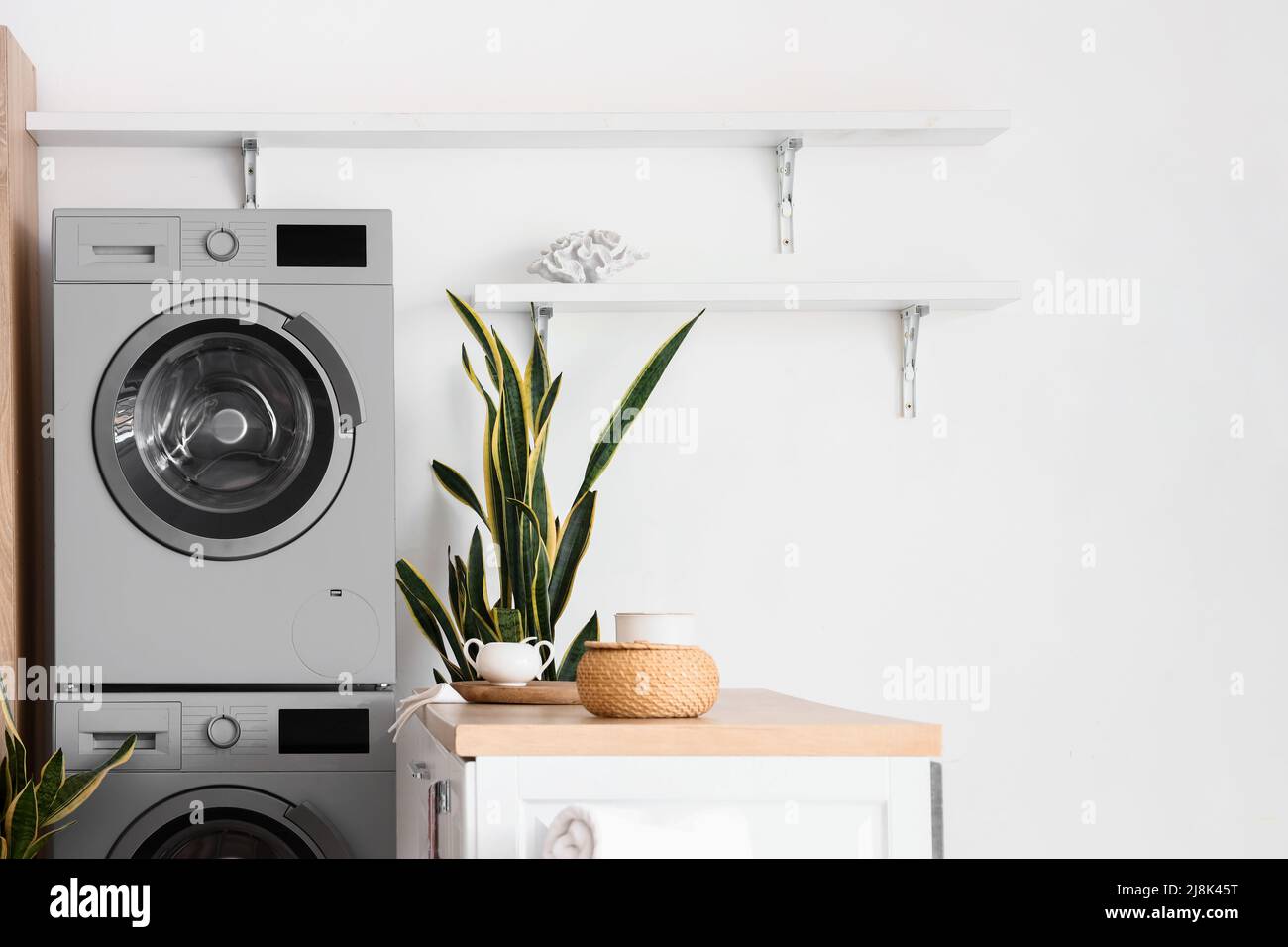 Modern washing machines near light wall in kitchen Stock Photo - Alamy