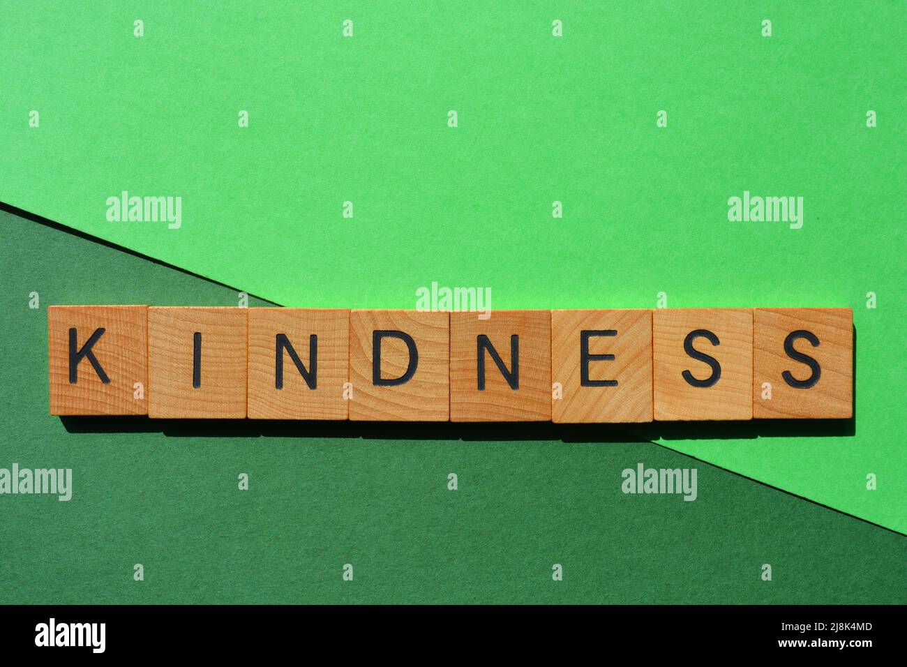 Kindness, word in wooden alphabet letters isolated on green background ...