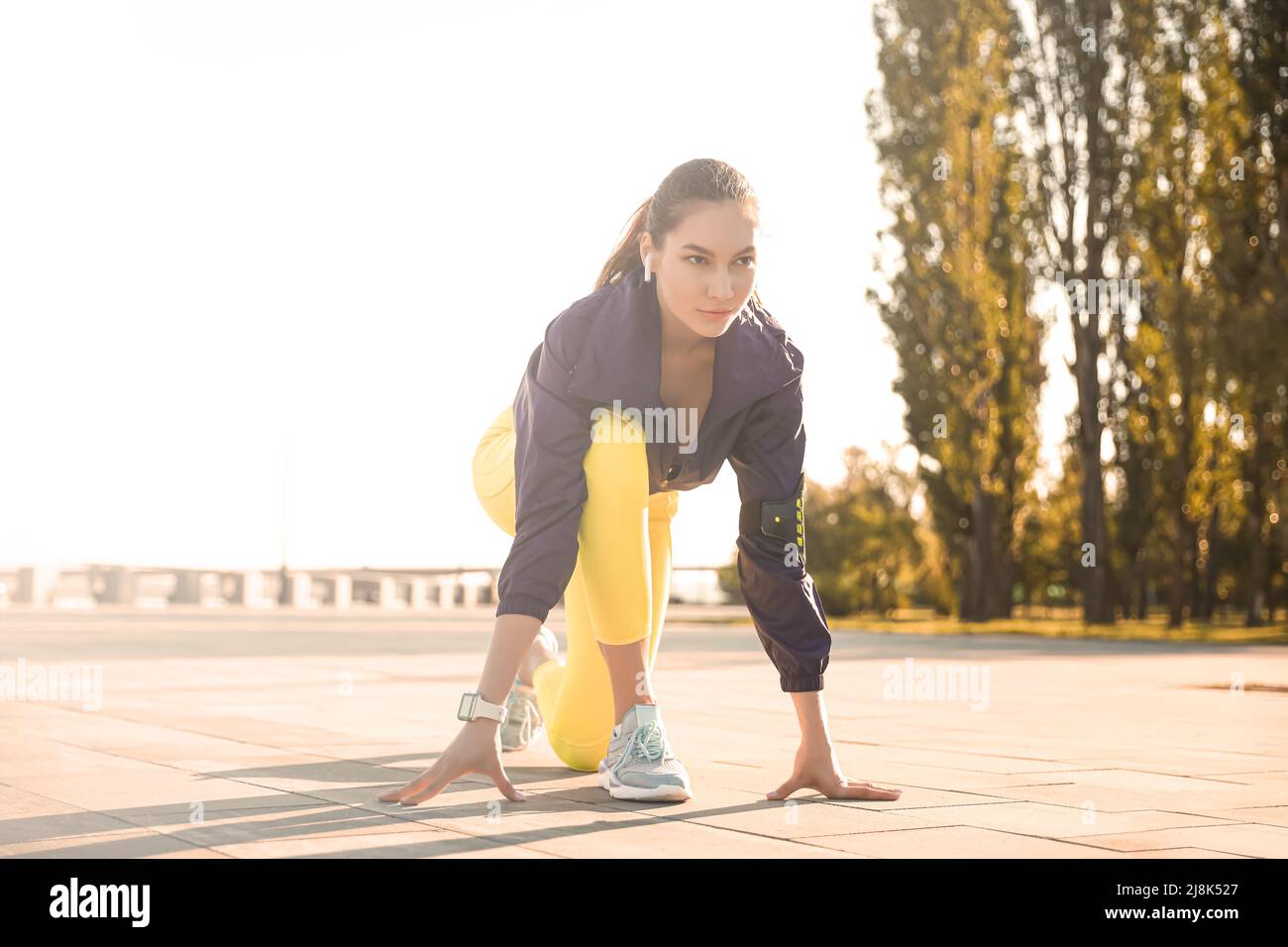 Sporty female runner in crouch start position outdoors Stock Photo - Alamy
