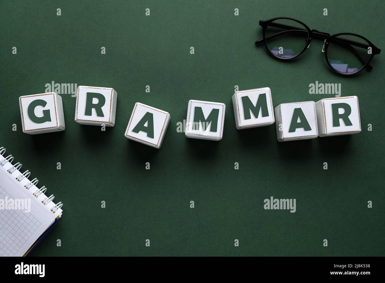 Word GRAMMAR made of cubes and glasses on green background, top view ...