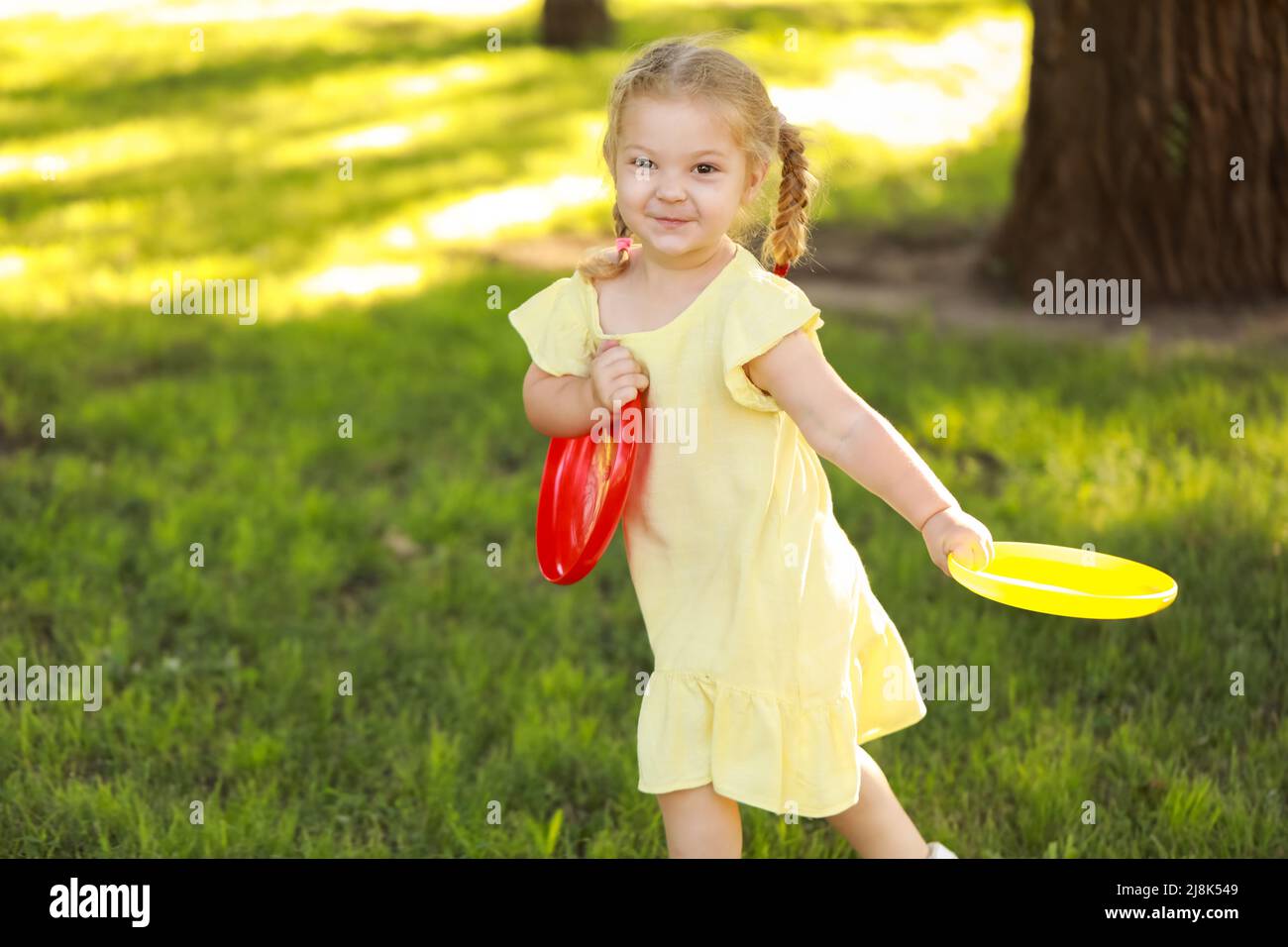 Cute little girl in dress playing frisbee in park Stock Photo - Alamy