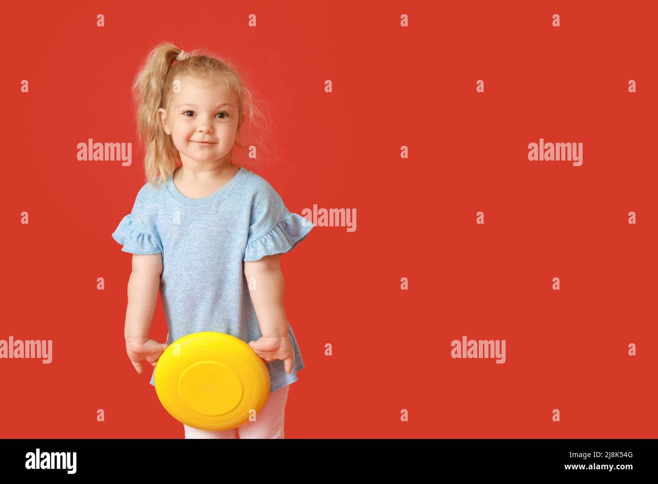 Cute little girl playing frisbee on red background Stock Photo - Alamy