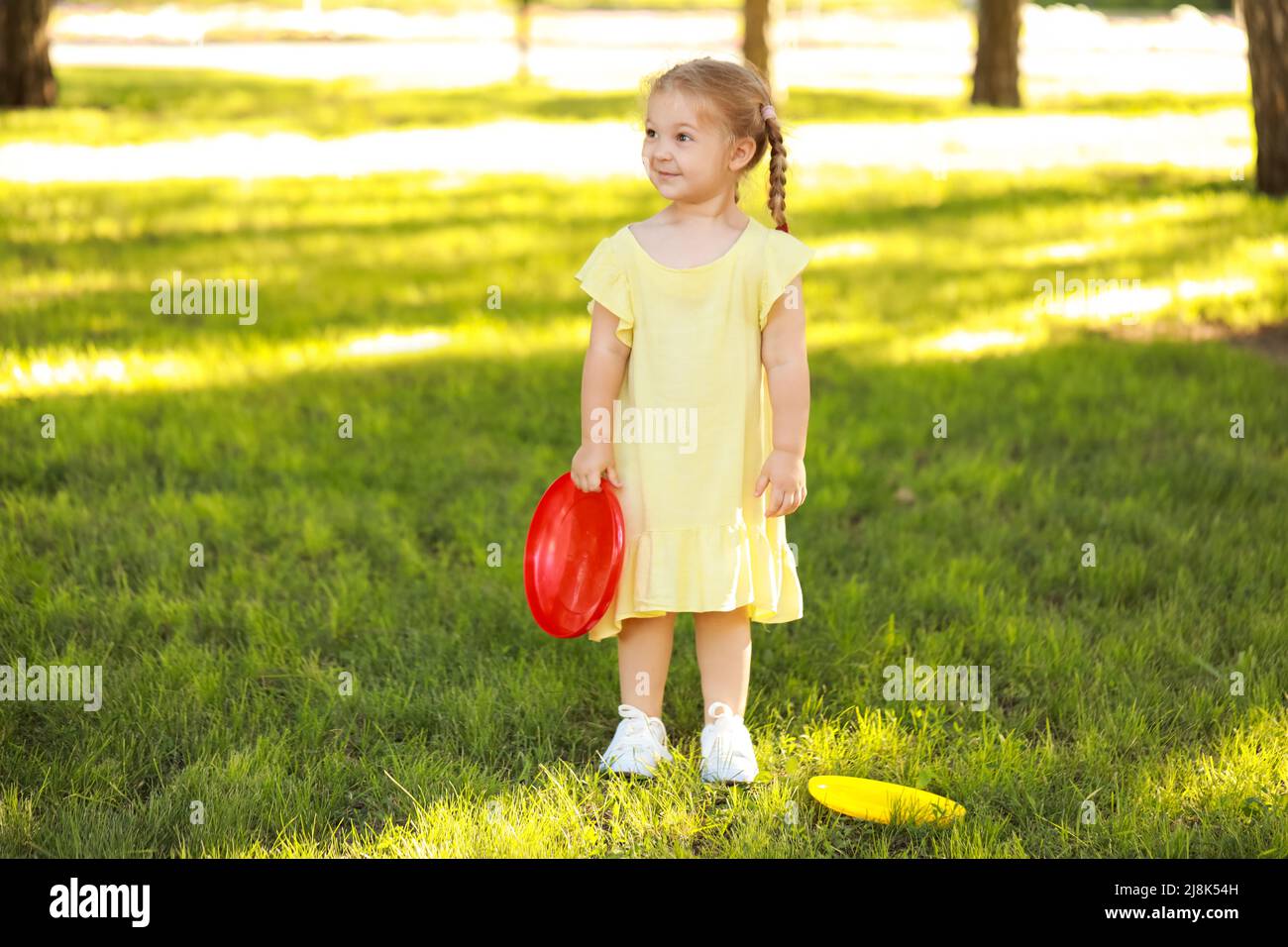 Cute little girl playing frisbee in park Stock Photo - Alamy