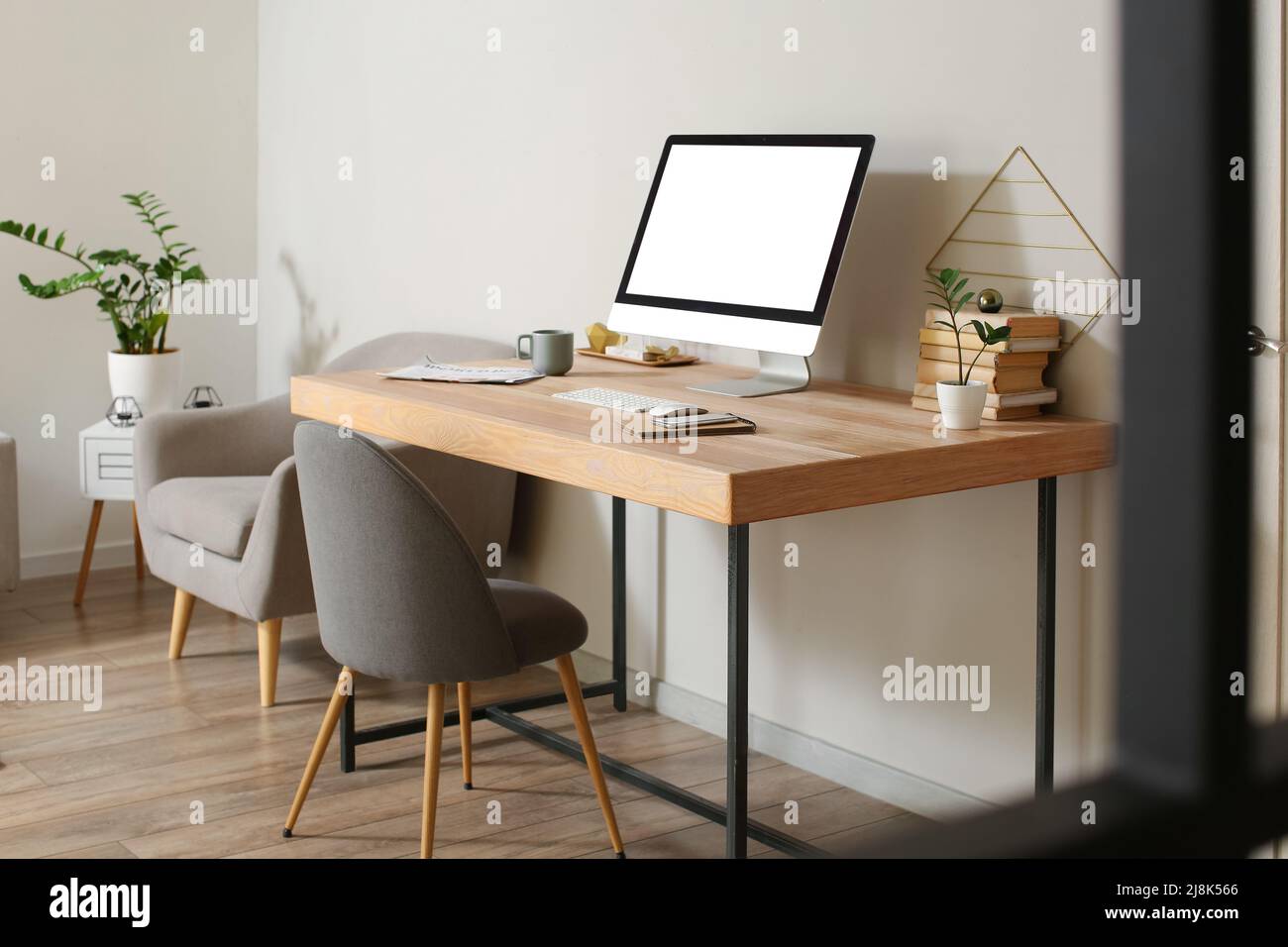 Modern computer and mobile phone on wooden standing desk near light ...