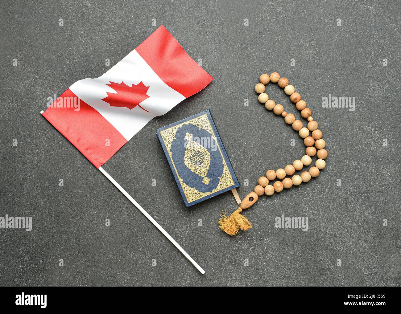 Canadian flag with Koran and Muslim prayer beads on dark background ...