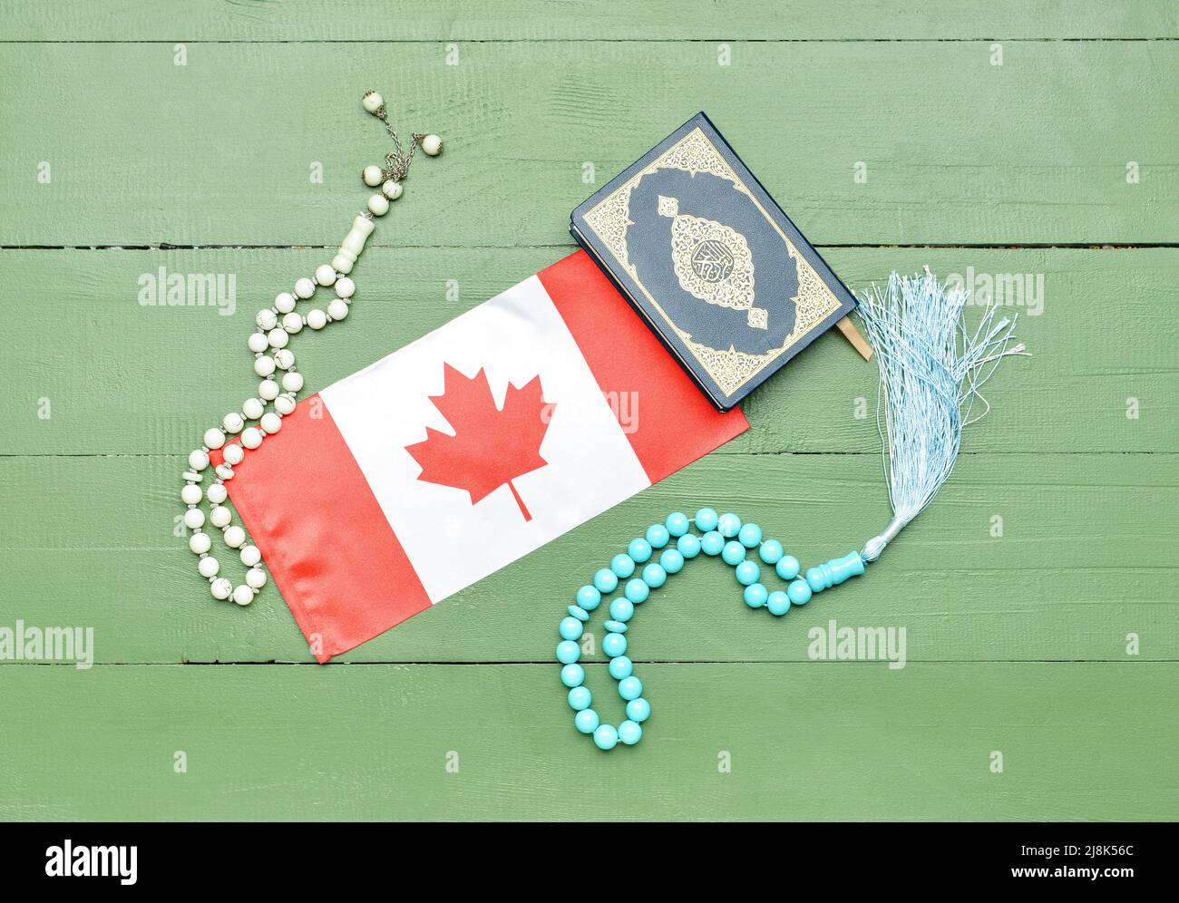 Canadian flag with Muslim prayer beads and Koran on green wooden ...