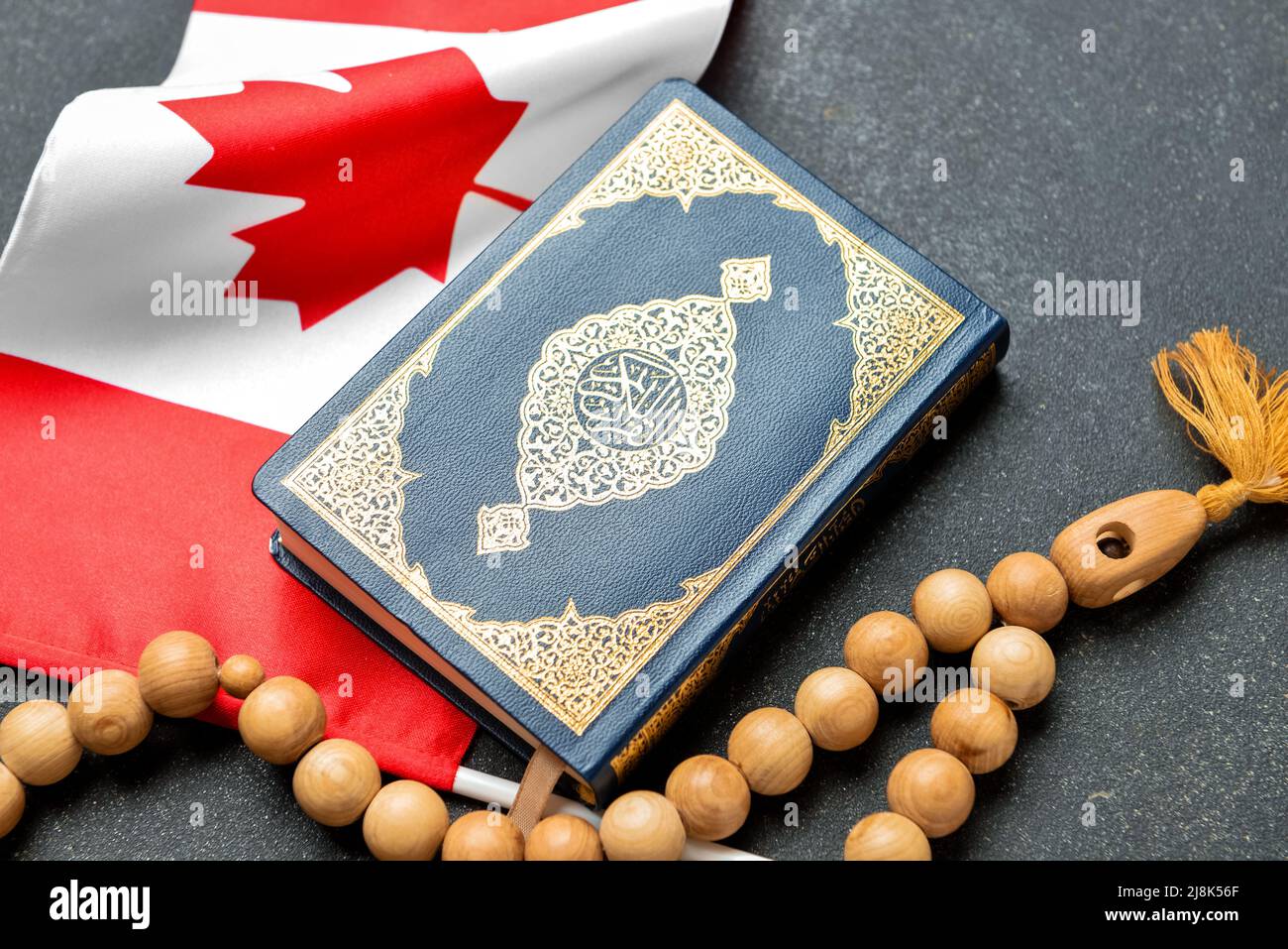Canadian flag with Koran and Muslim prayer beads on dark background ...