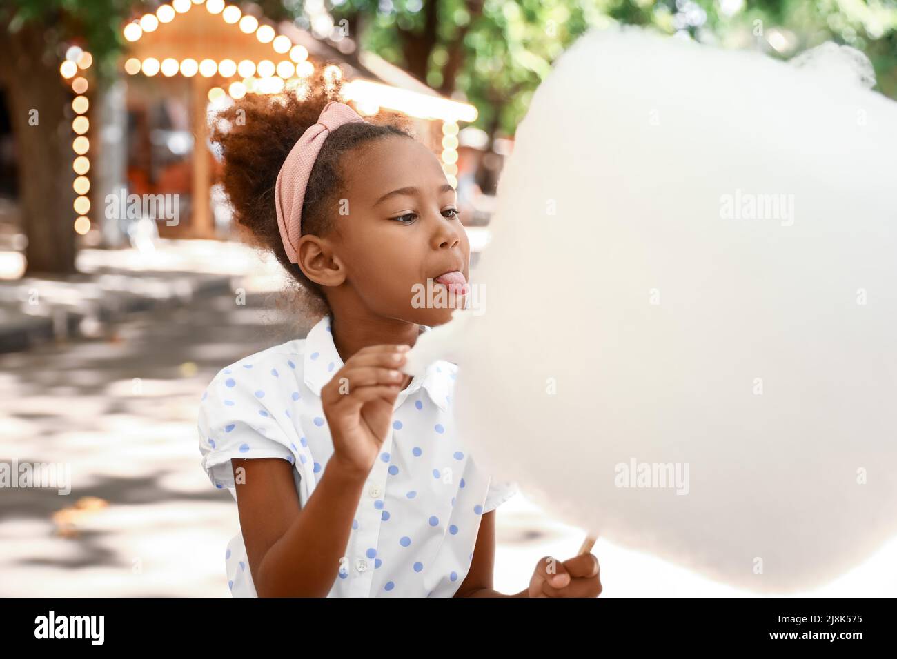 Little African-American girl eating cotton candy outdoors Stock Photo ...