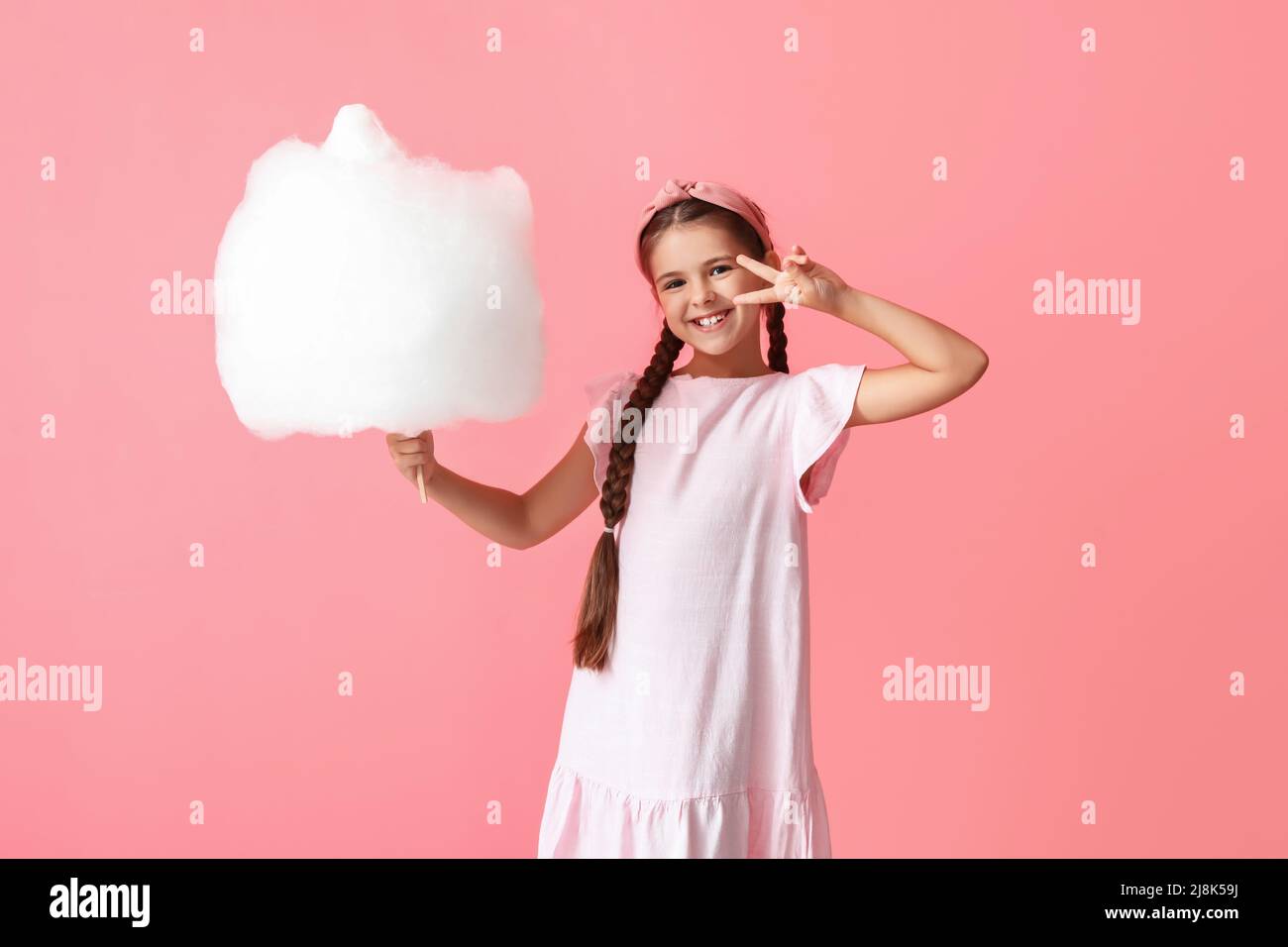 Cute little girl with cotton candy on pink background Stock Photo - Alamy