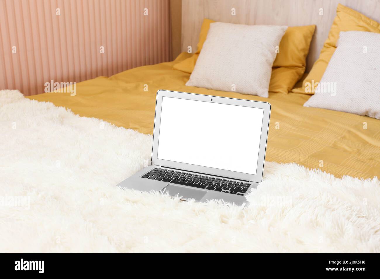 Laptop with blank screen on stylish bed in room Stock Photo - Alamy