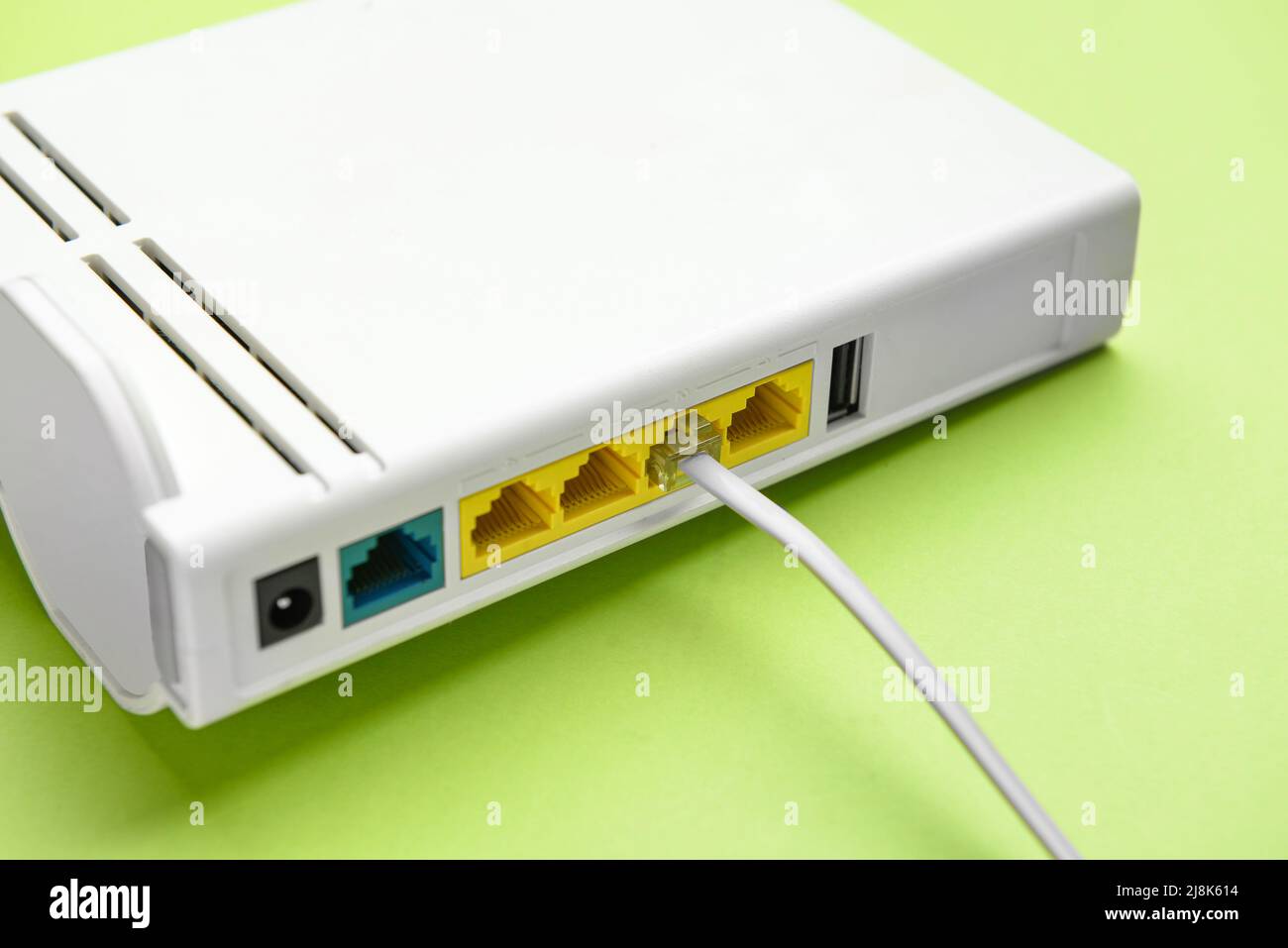 Modern wi-fi router and internet cable on green background, closeup ...