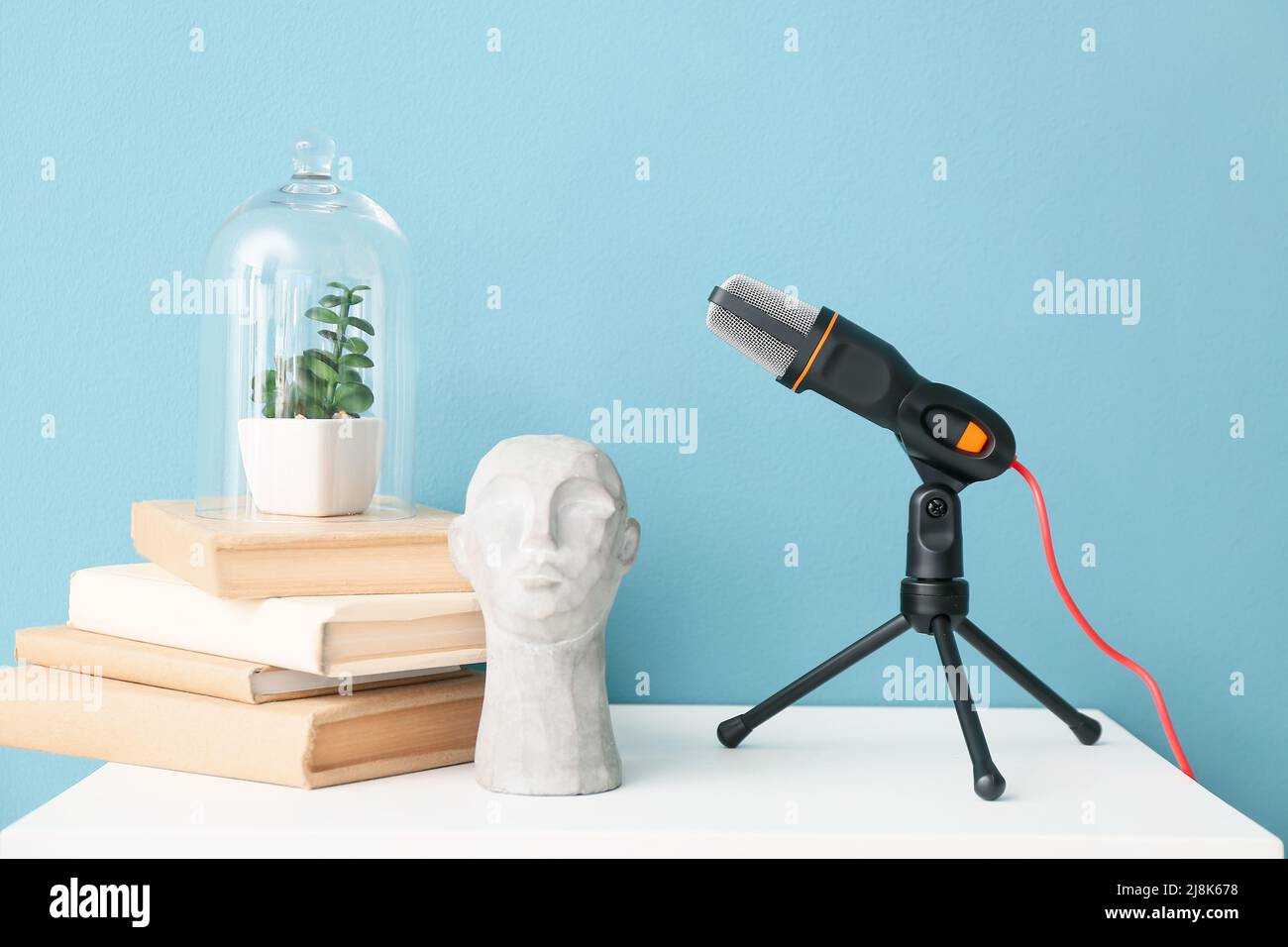 Modern professional microphone, stack of books and decor on table near ...
