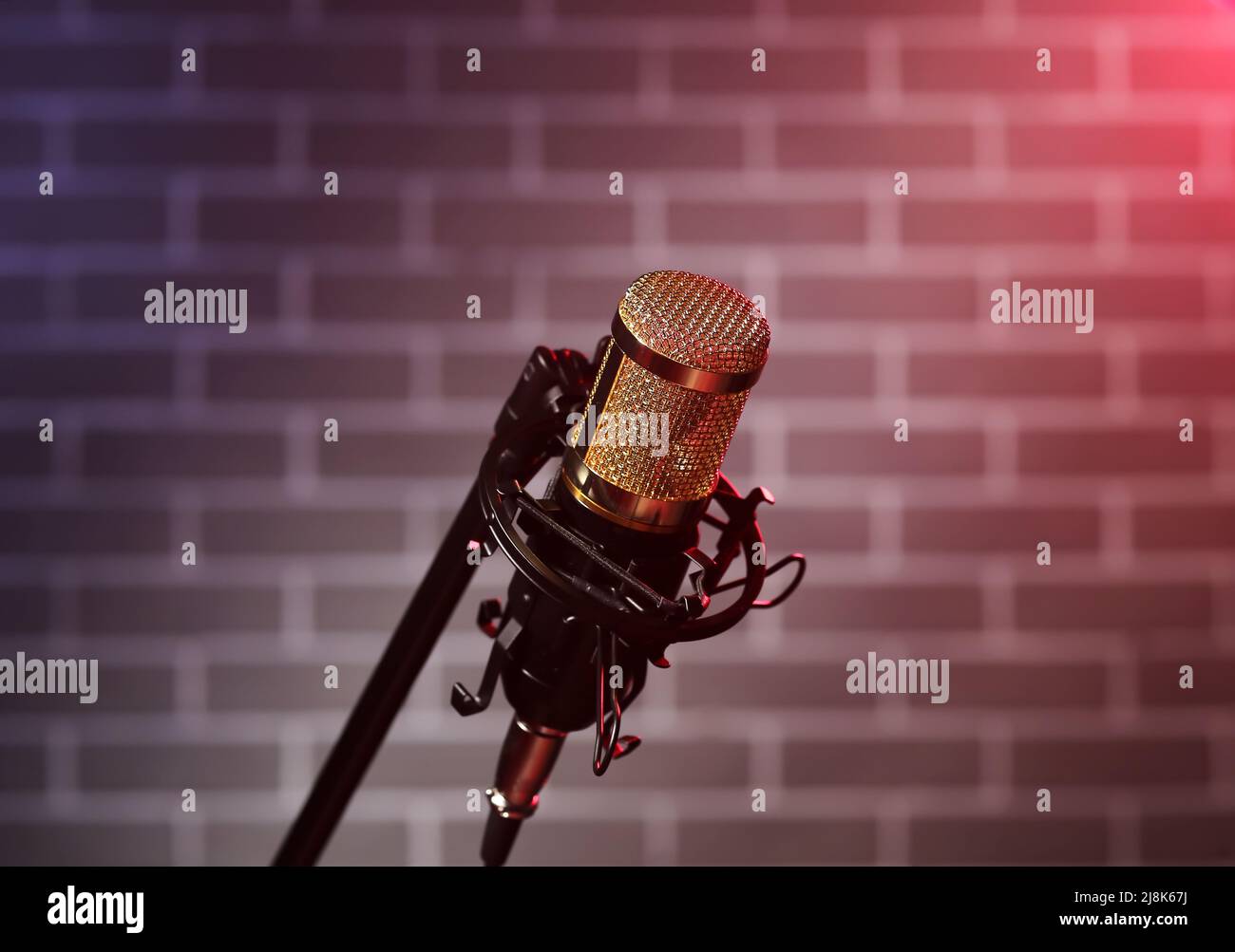 Closeup view of stand with professional microphone on dark brick wall ...