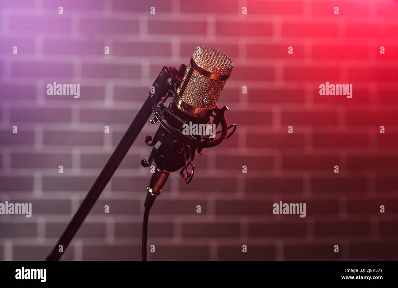 Stand with modern professional microphone on dark brick wall background ...