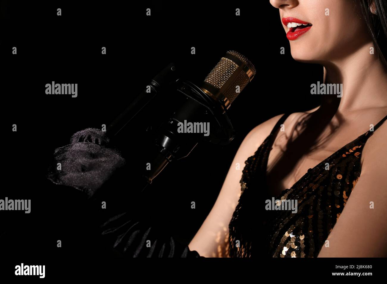 Female singer with professional microphone on dark background, closeup ...