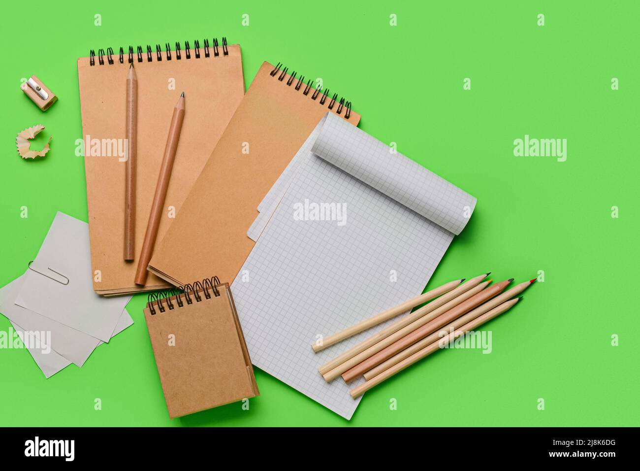 Notebooks with pencils, sticky notes and sharpener on green background ...