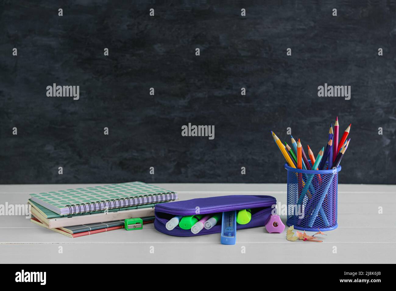 Different stationery on table near black wall Stock Photo - Alamy