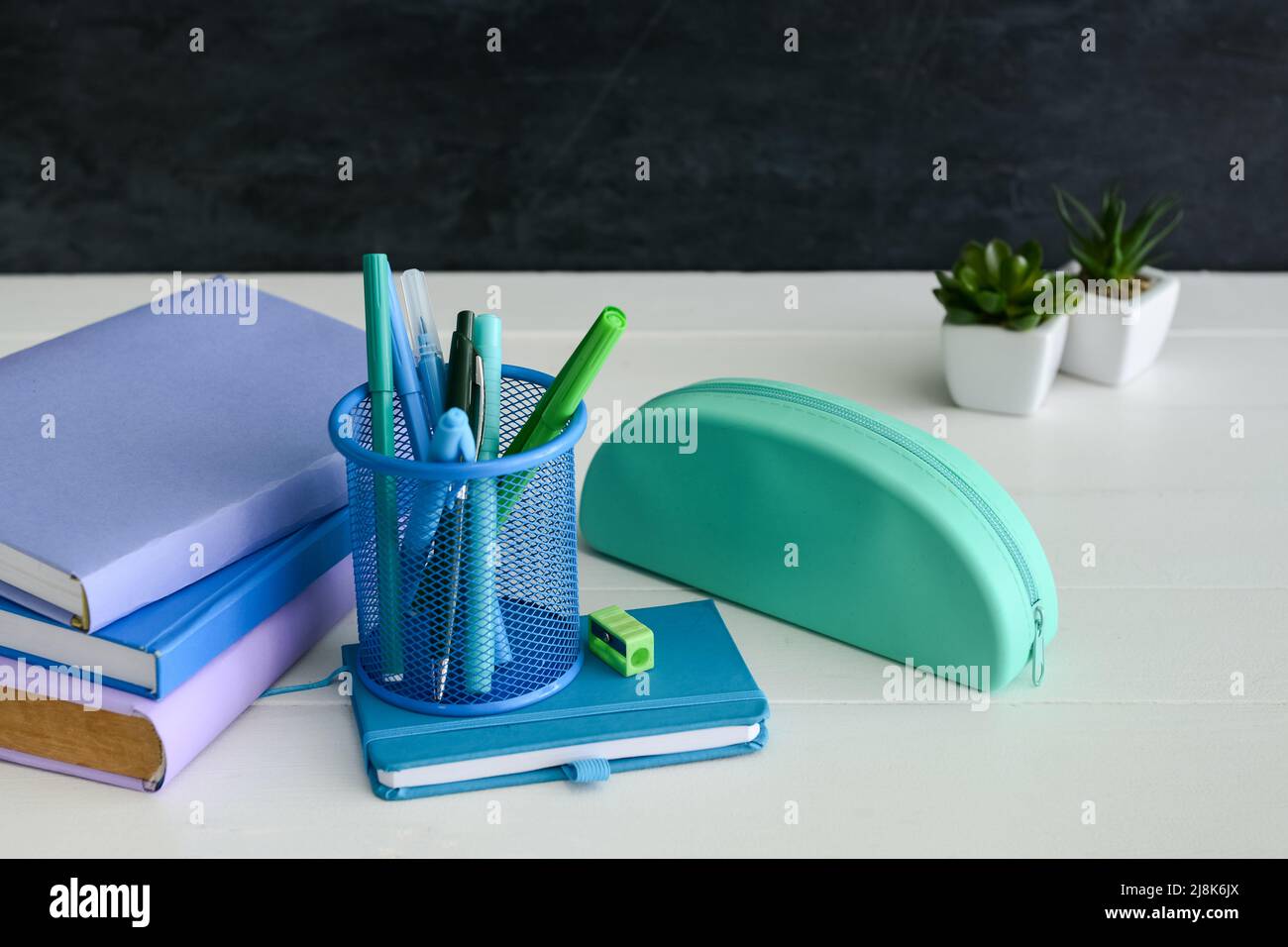 Different stationery on table near black wall Stock Photo - Alamy