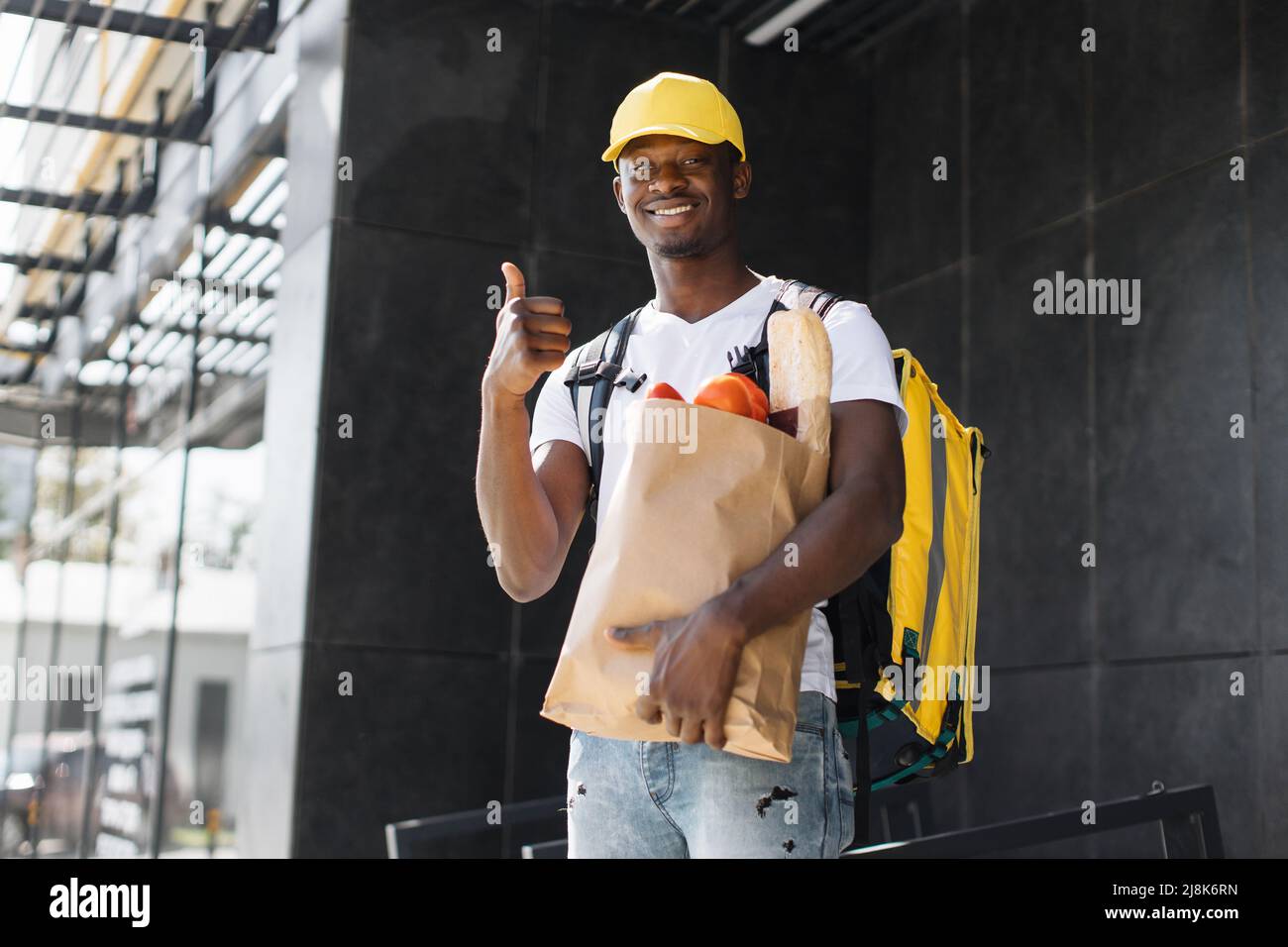 Delivery concept. African American courier standing with a package with ...
