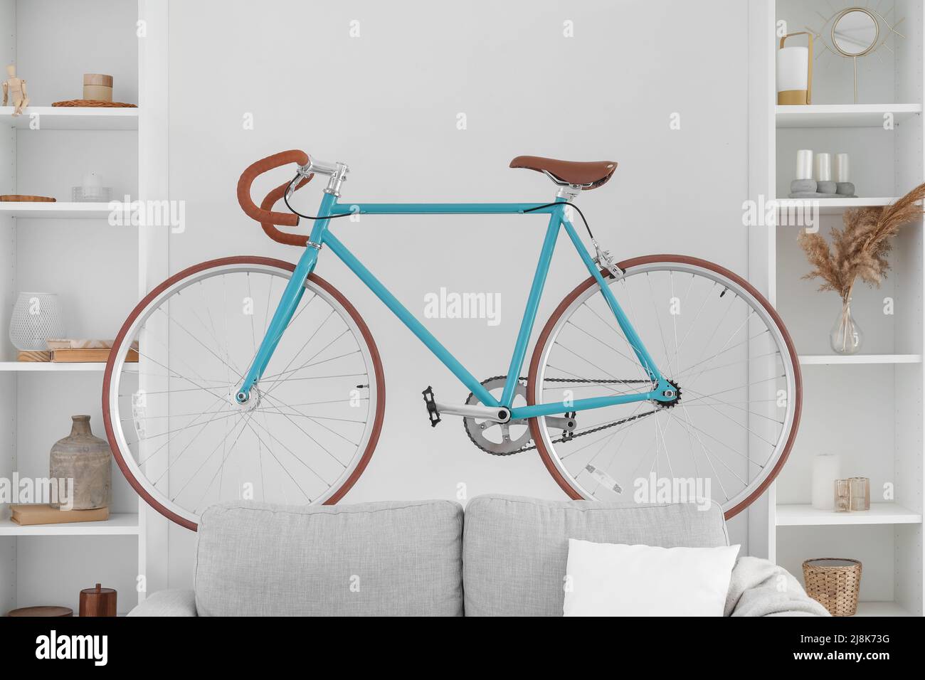 Modern bicycle on grey sofa in light living room Stock Photo - Alamy
