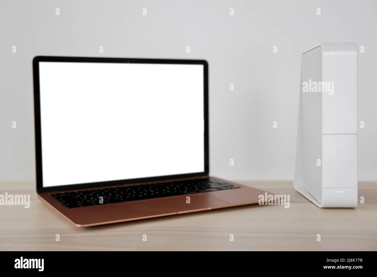 Modern laptop and wi-fi router on table near white wall Stock Photo - Alamy