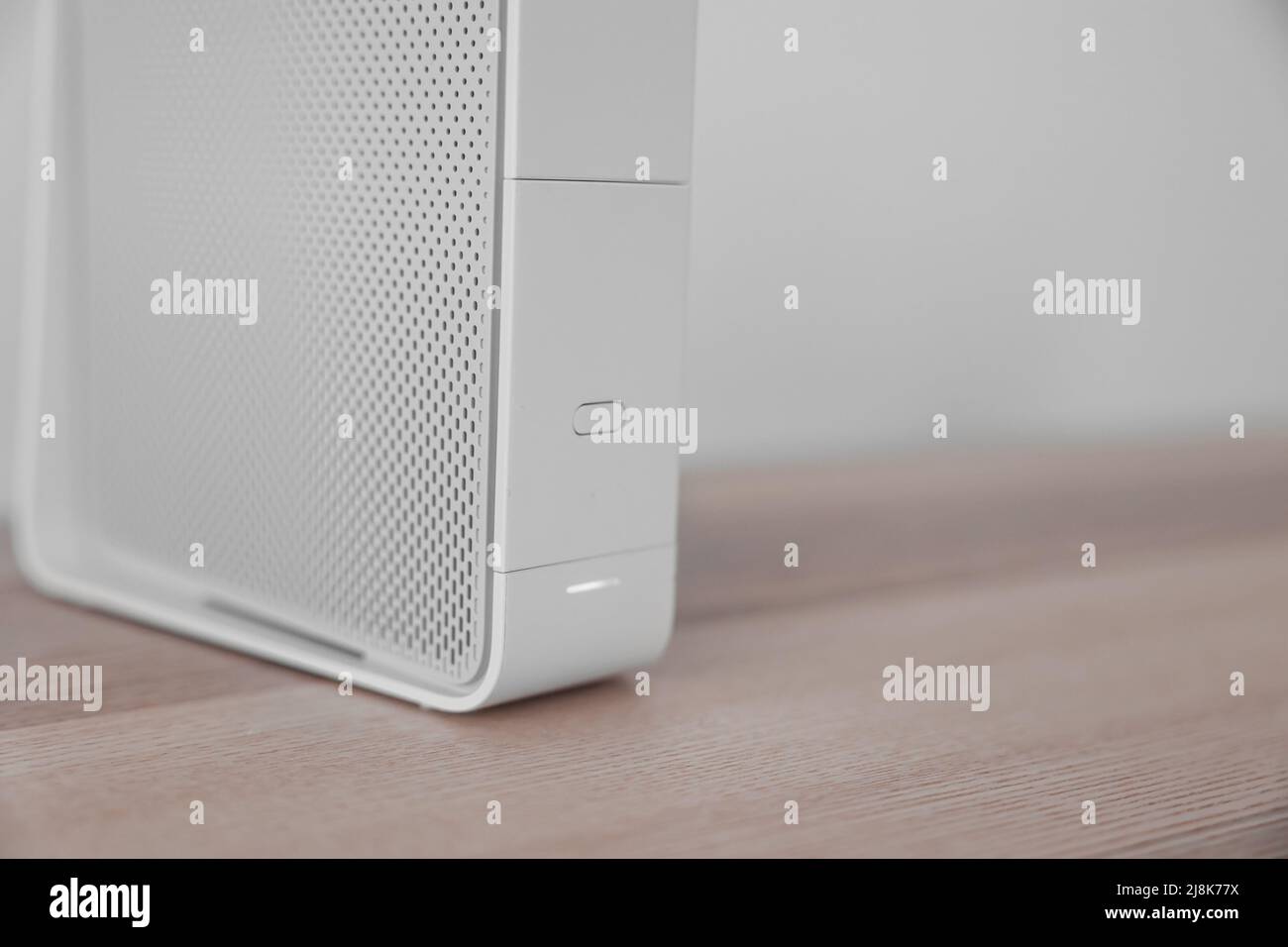 Modern white wi-fi router on table near light wall, closeup Stock Photo ...