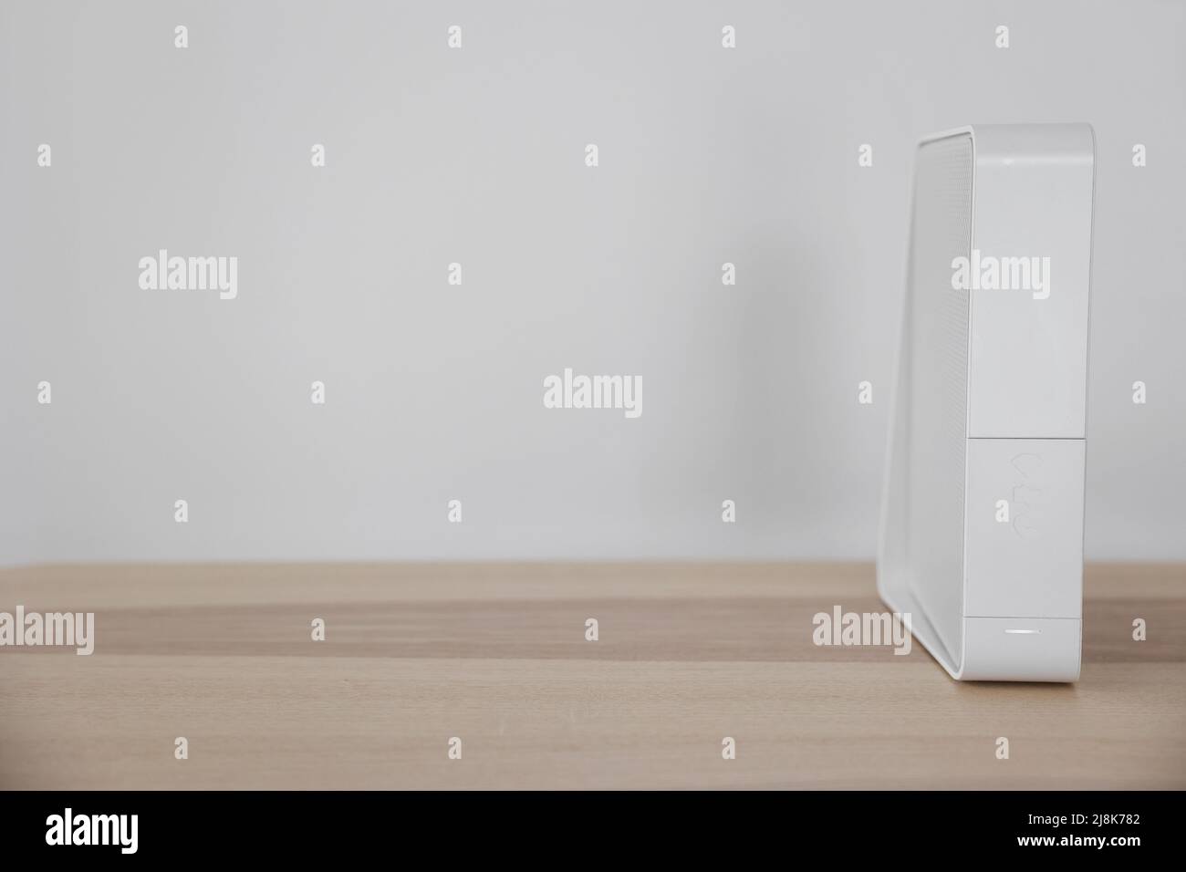 Modern white wi-fi router on table near light wall Stock Photo - Alamy