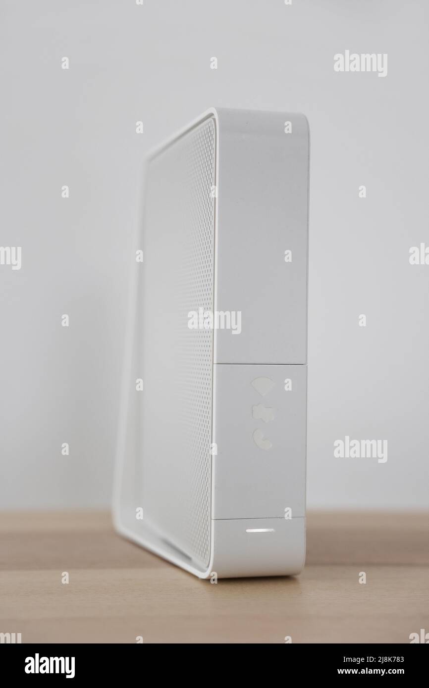 Modern white wi-fi router on table near light wall Stock Photo - Alamy