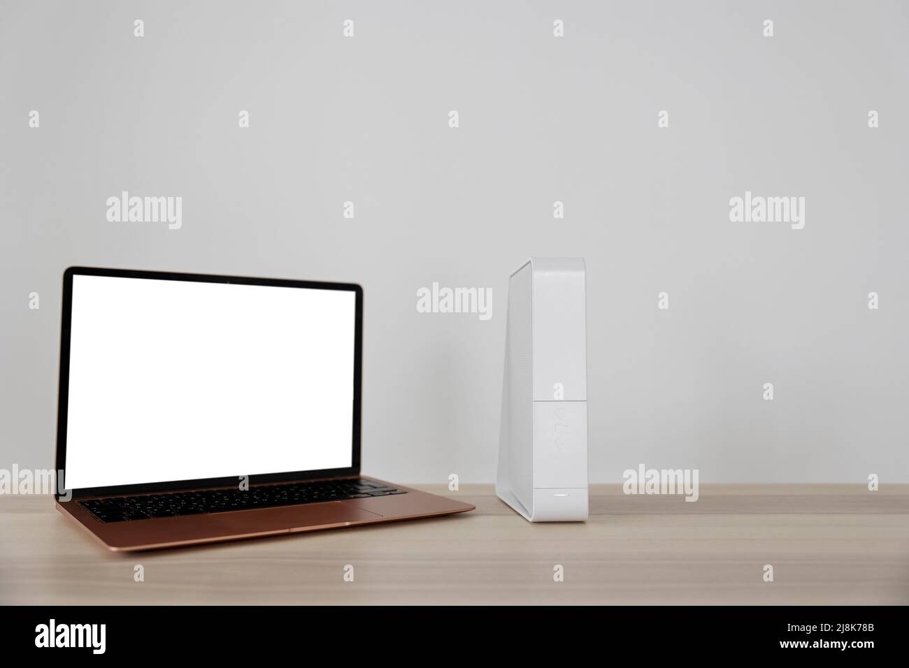 Modern laptop and wi-fi router on table near white wall Stock Photo - Alamy