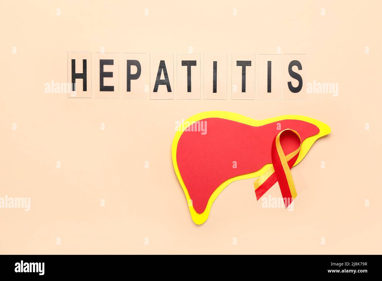 Awareness ribbon with word HEPATITIS and paper liver on beige ...