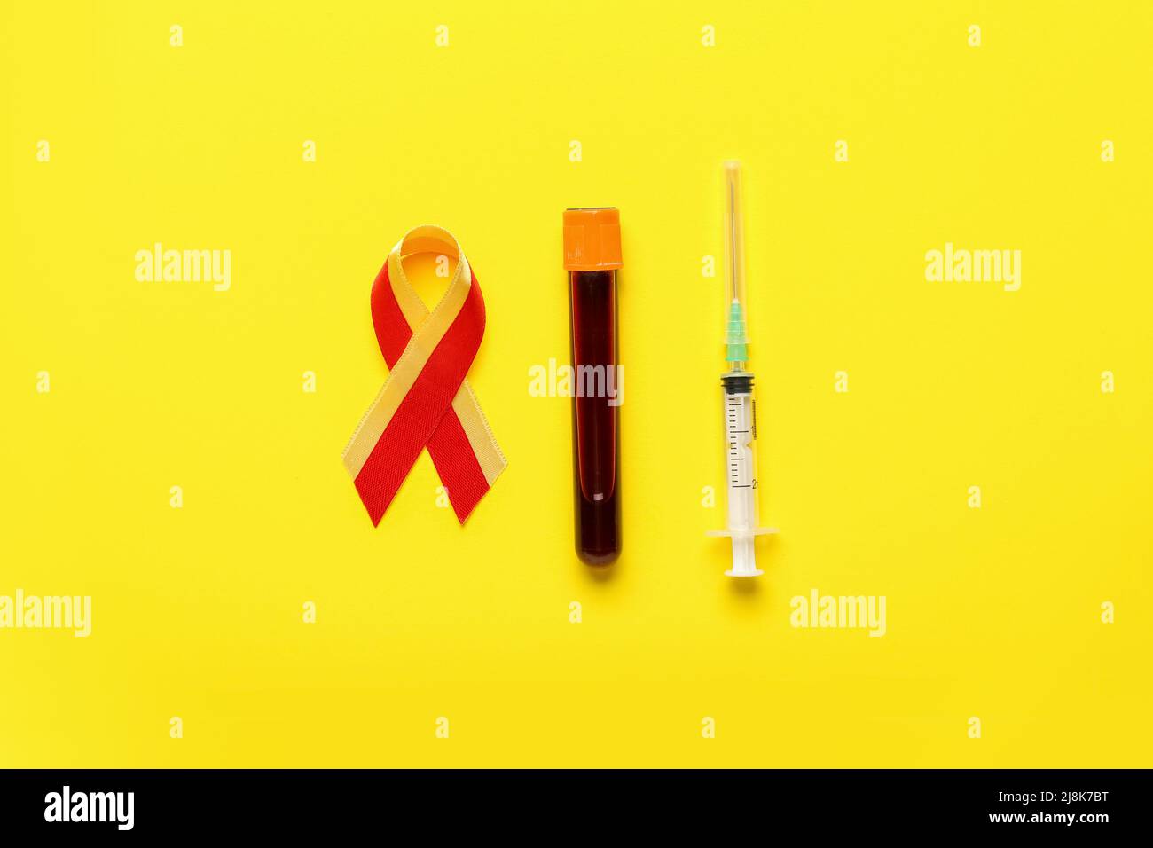 Awareness ribbon with blood sample and syringe on yellow background ...