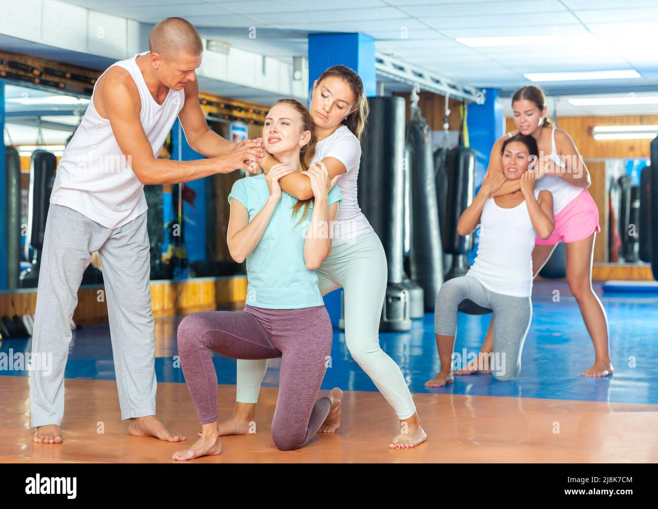 Self-defense instructor teaching women to perform guillotine choke ...