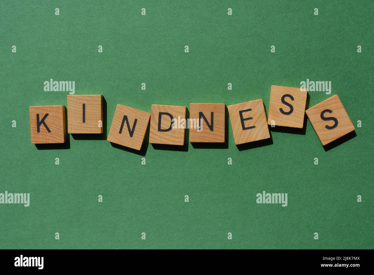 Kindness, word in wood alphabet letters isolated on breen background ...